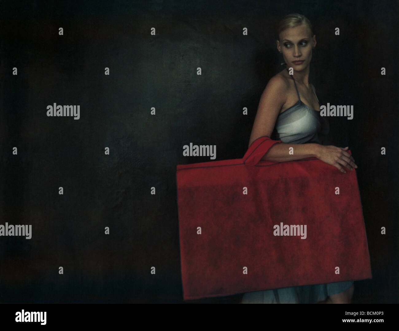 Woman holding red portfolio case on arm, looking over shoulder Stock ...