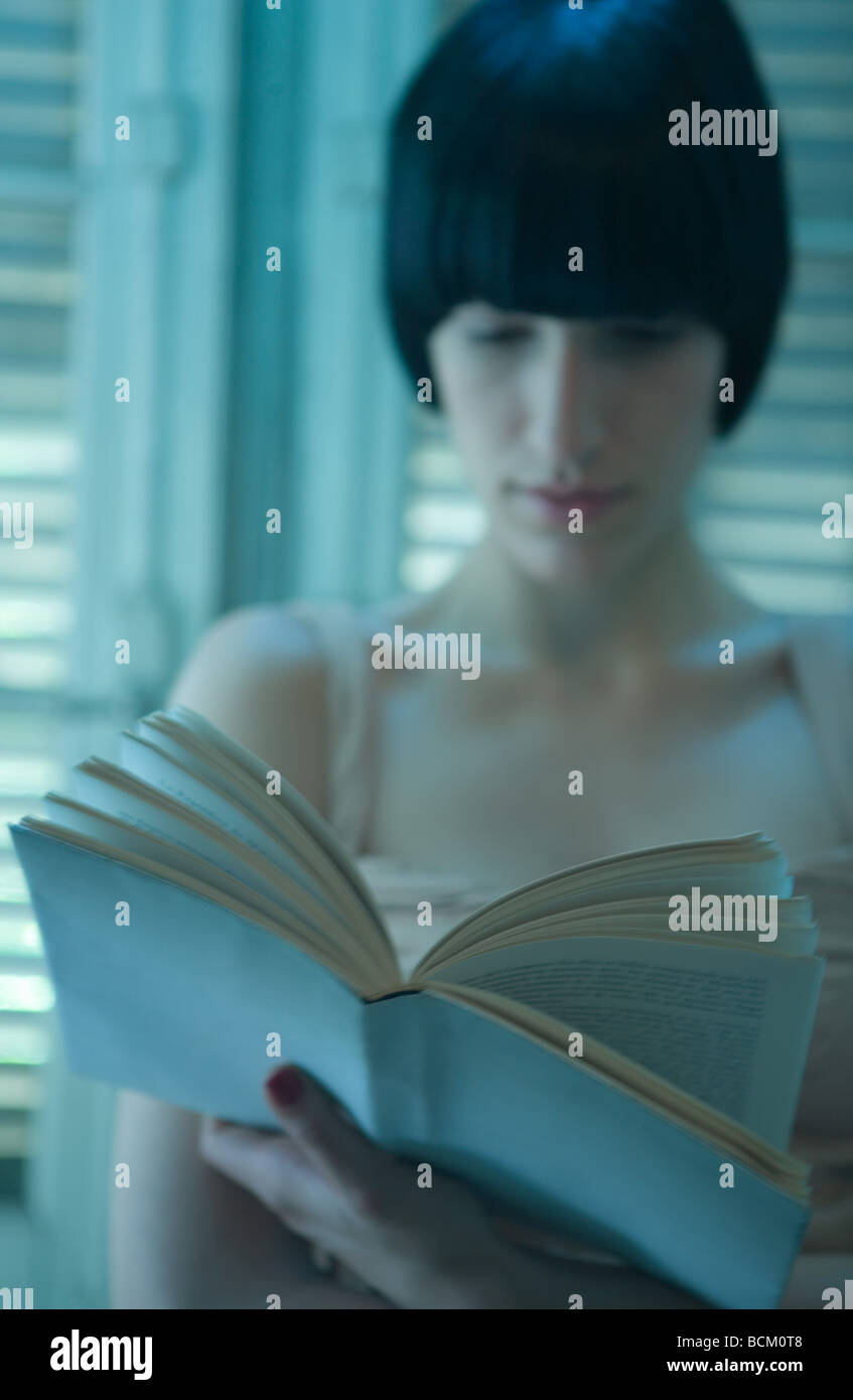Woman reading book, focus on book in foreground Stock Photo - Alamy