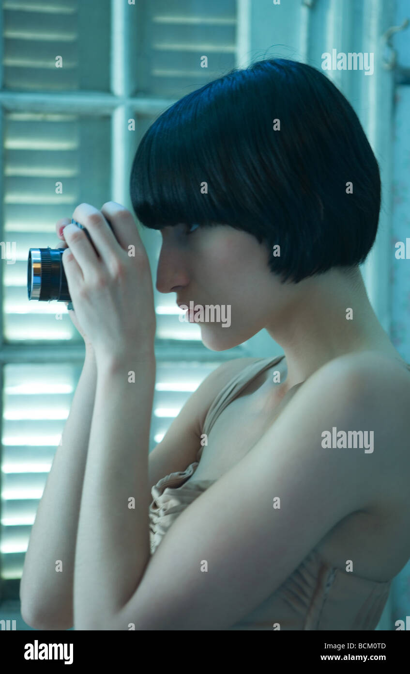 Woman taking photograph, looking through camera, side view Stock Photo ...