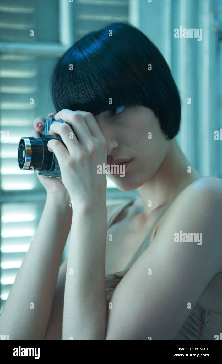Woman taking photograph, looking through camera Stock Photo - Alamy