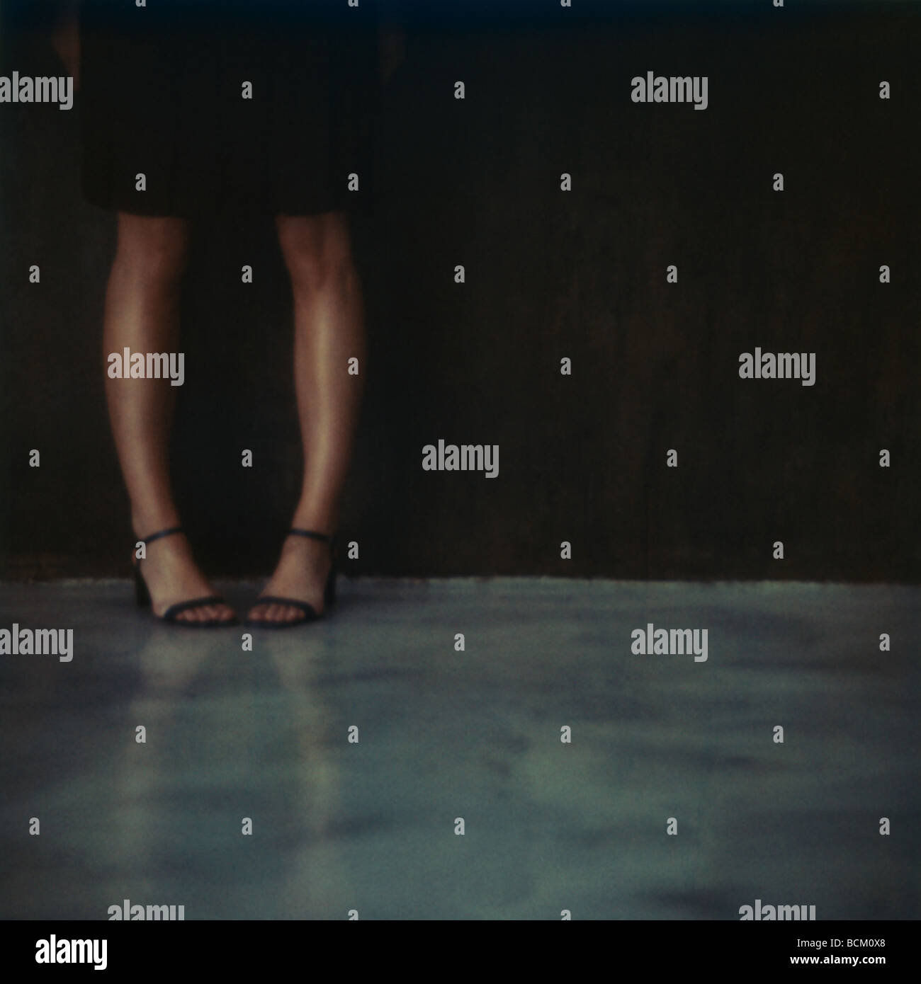 Woman wearing dress and heeled sandals, feet turned inward, low section ...