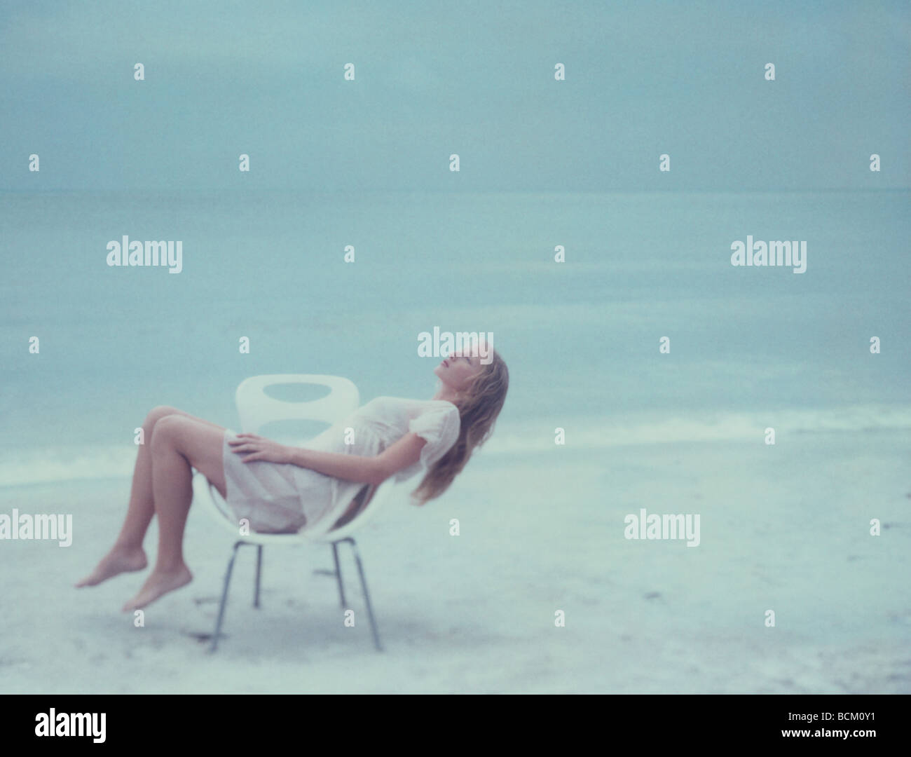 Young female lying sideways in chair on beach, full length Stock Photo ...