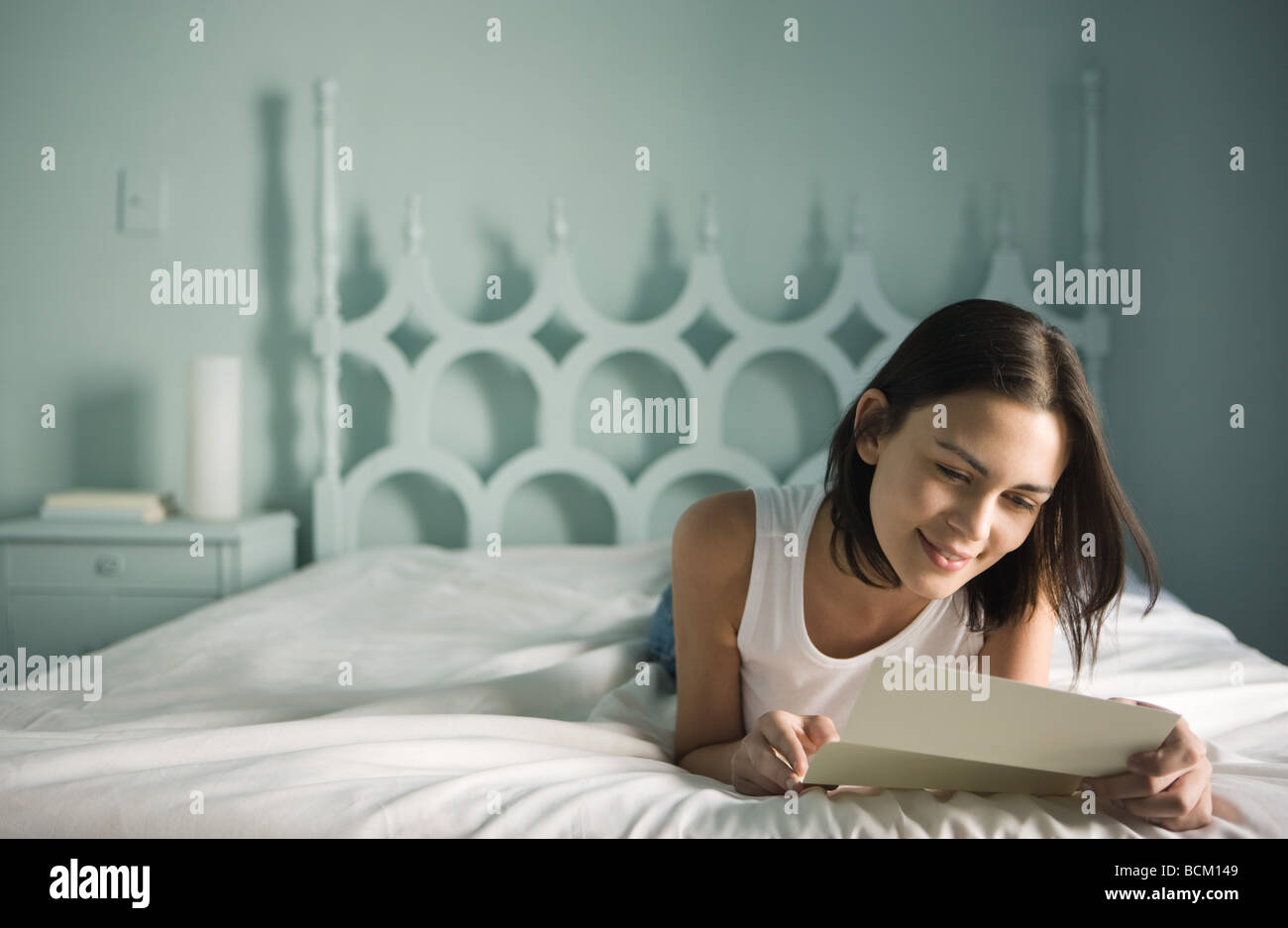 Woman lying on bed reading letter Stock Photo - Alamy