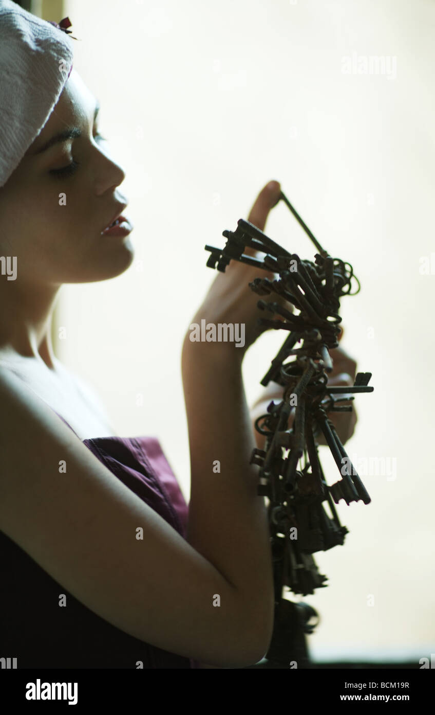 Woman holding up keys, looking down, side view, close-up Stock Photo ...