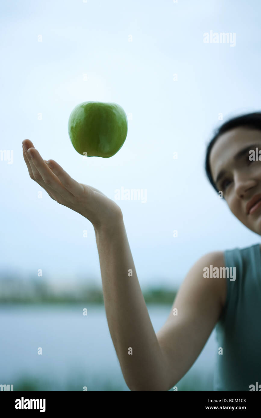Apple floating in air above woman's hand, cropped view Stock Photo - Alamy