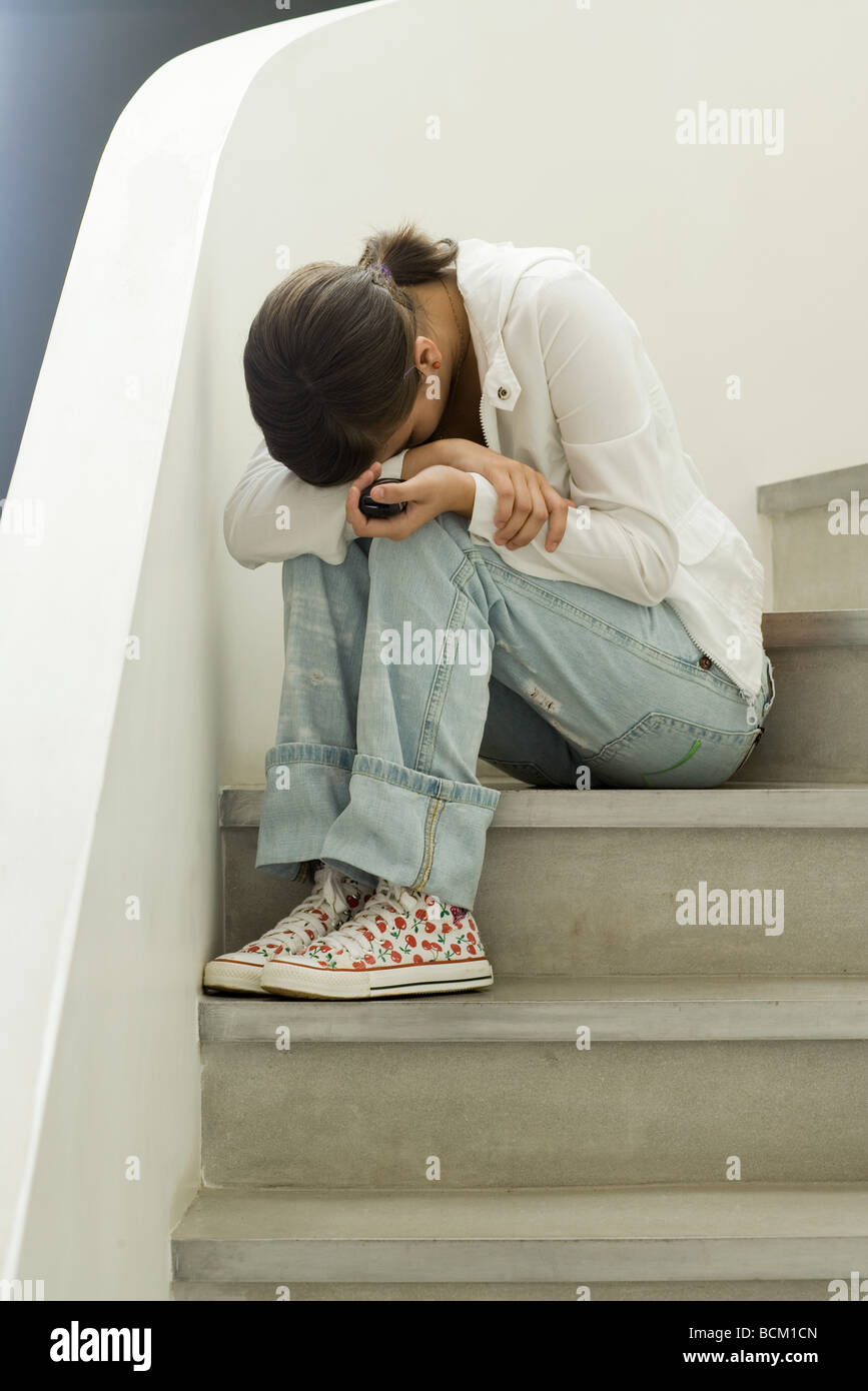 Teen girl sitting on stairs, head down on arms, full length Stock Photo ...