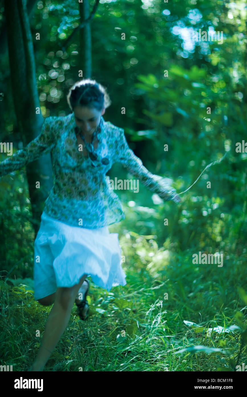 Young woman looking down, running through forest Stock Photo - Alamy