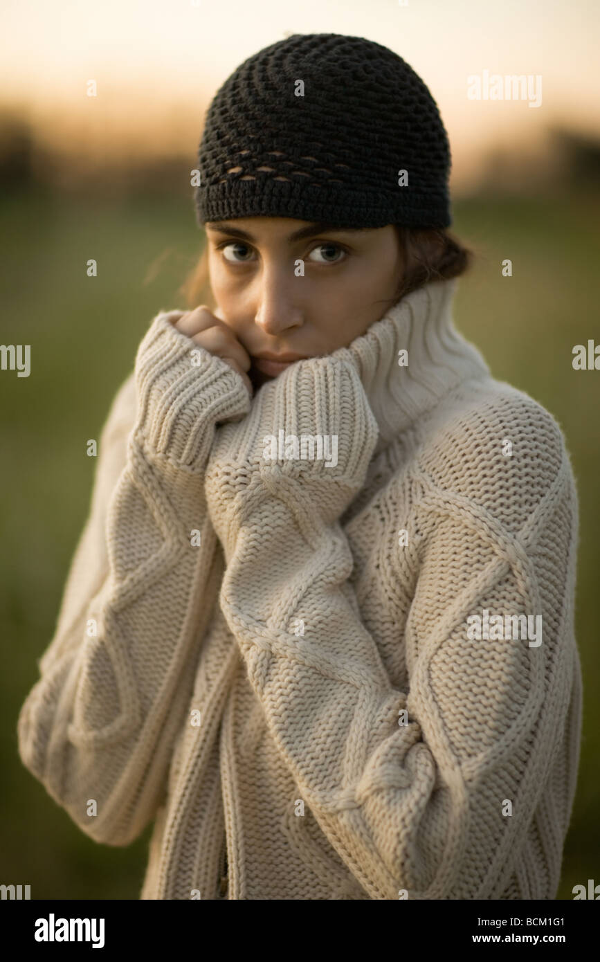 Woman standing outdoors wearing thick sweater, looking at camera ...