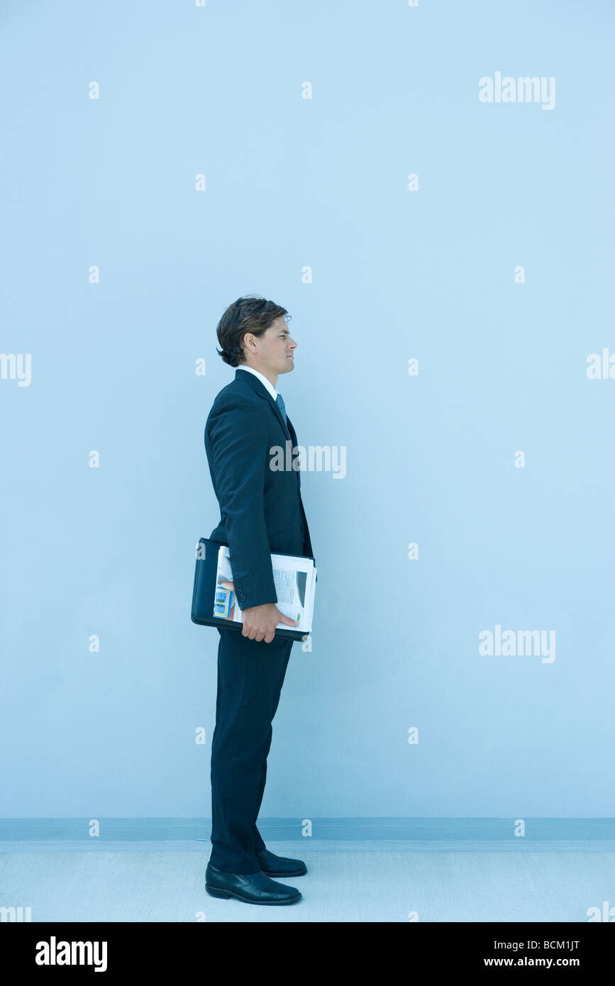 Businesman standing, holding binder under arm, full length Stock Photo ...
