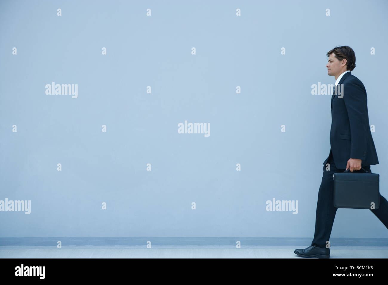 Businessman carrying briefcase, full length, side view Stock Photo - Alamy