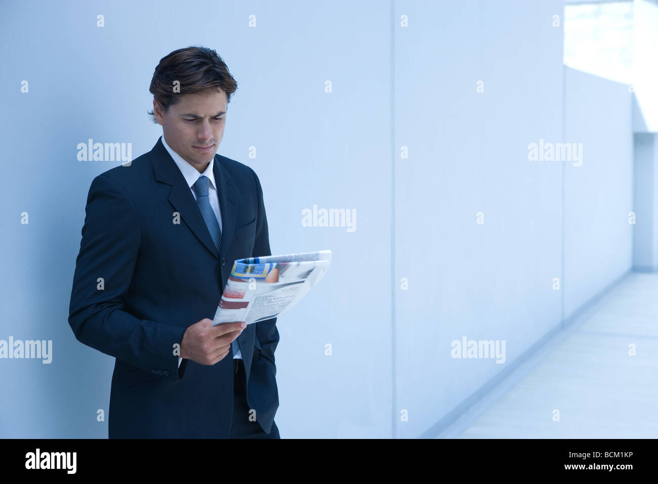 Businessman standing, reading newspaper Stock Photo - Alamy