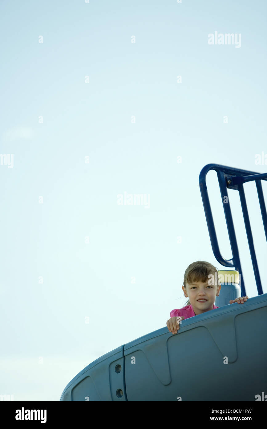 Girl sitting at top of slide, looking at camera, low angle view Stock ...