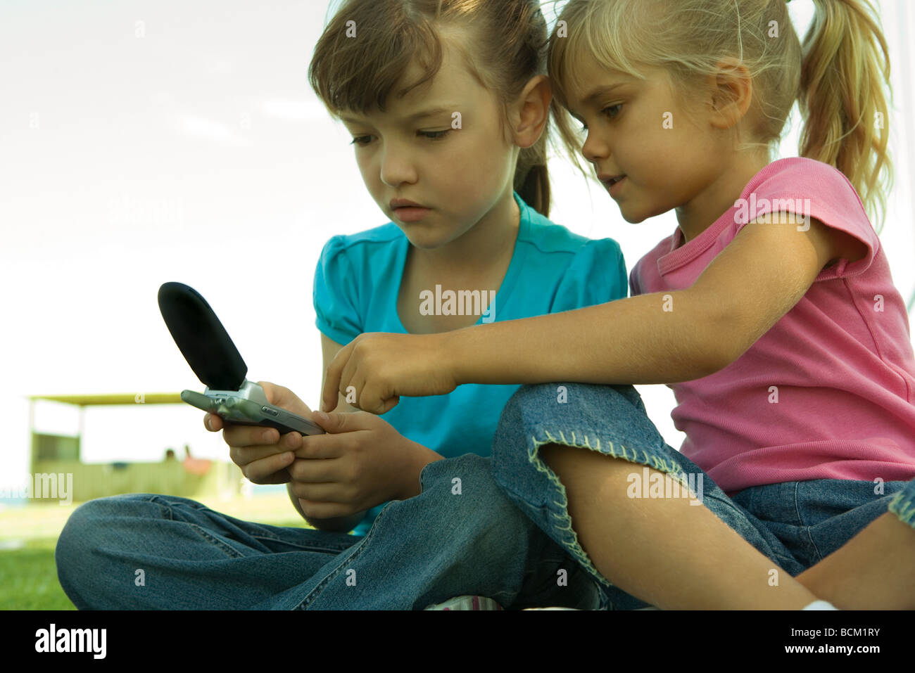 Girls using cell phone together, low angle view Stock Photo - Alamy