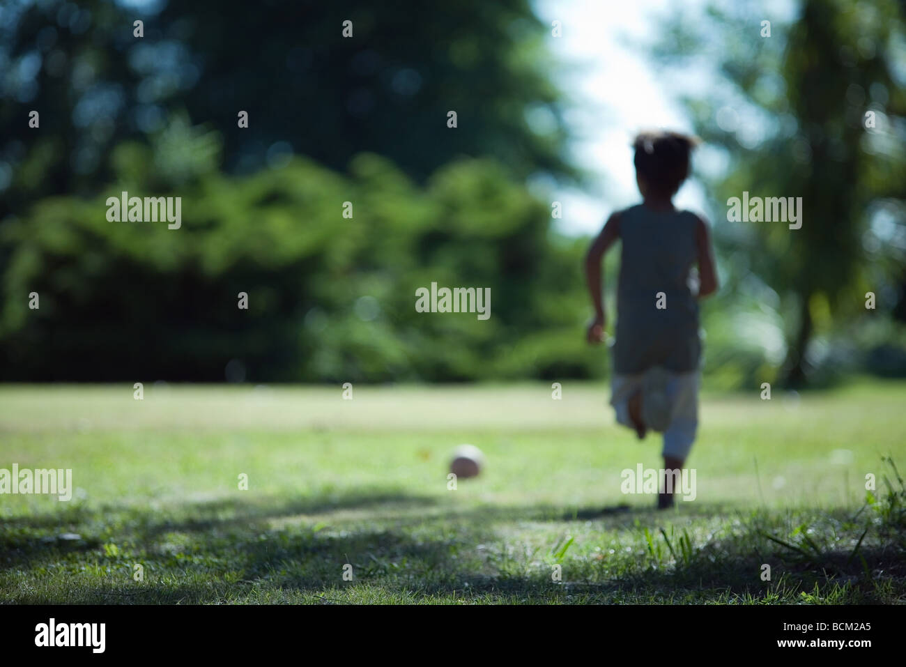 Little boy running outdoors, chasing ball, rear view Stock Photo - Alamy