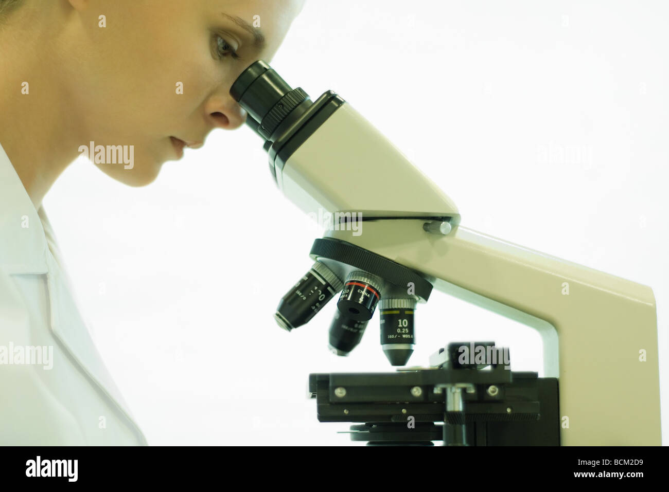 Female scientist looking through microscope, side view Stock Photo - Alamy