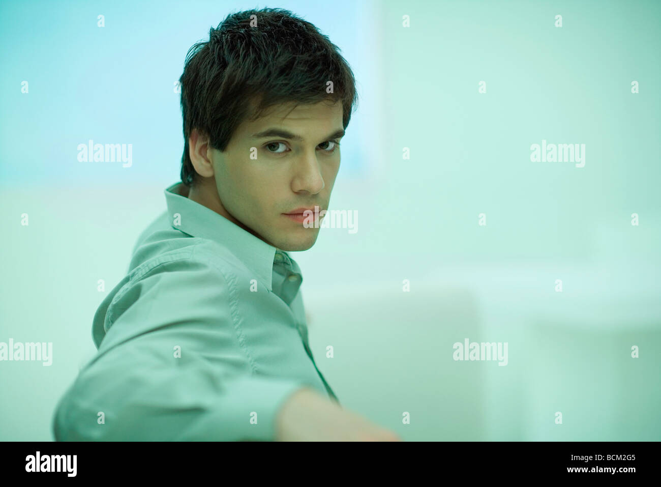 Young man staring over shoulder at camera Stock Photo - Alamy