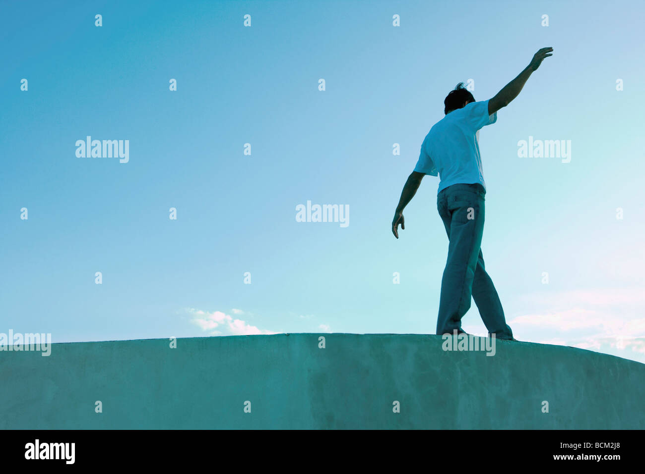 Man walking on ledge, arms out, low angle view Stock Photo - Alamy