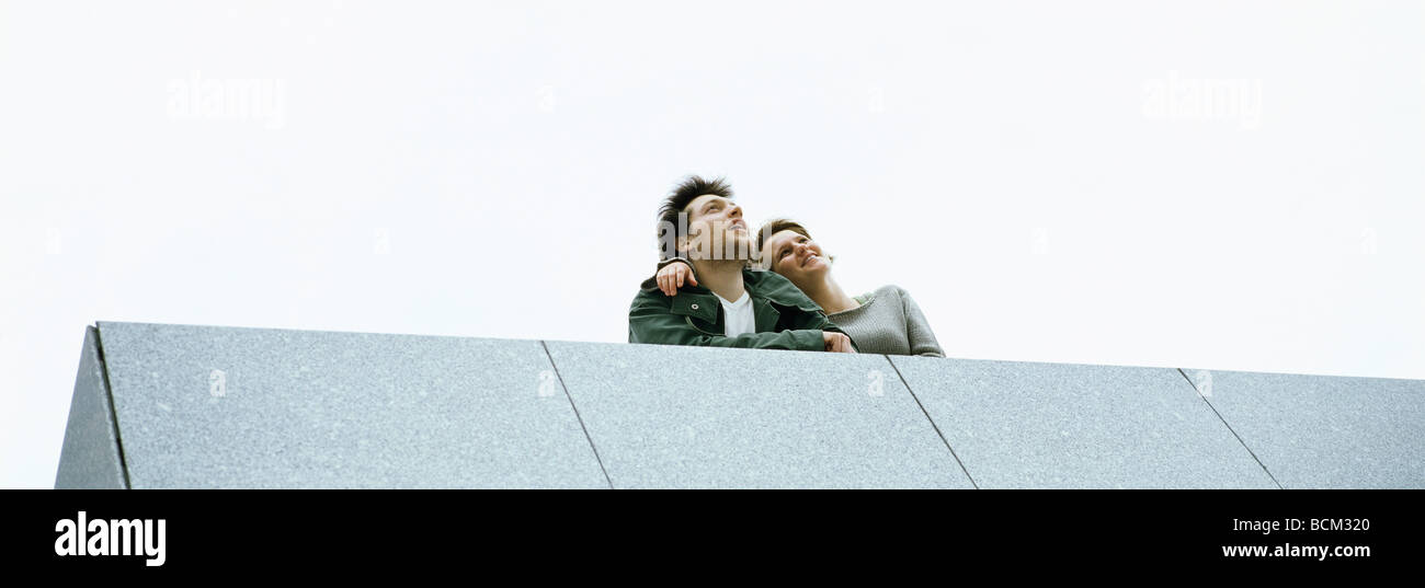 Young couple on balcony, looking up, low angle view Stock Photo - Alamy