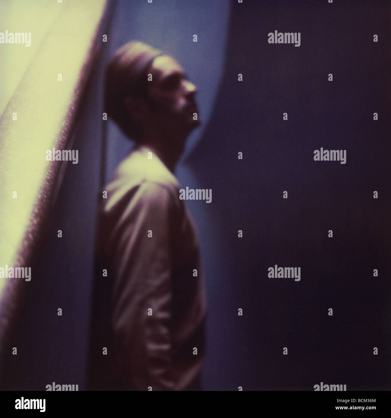 Man leaning against wall, looking up Stock Photo - Alamy