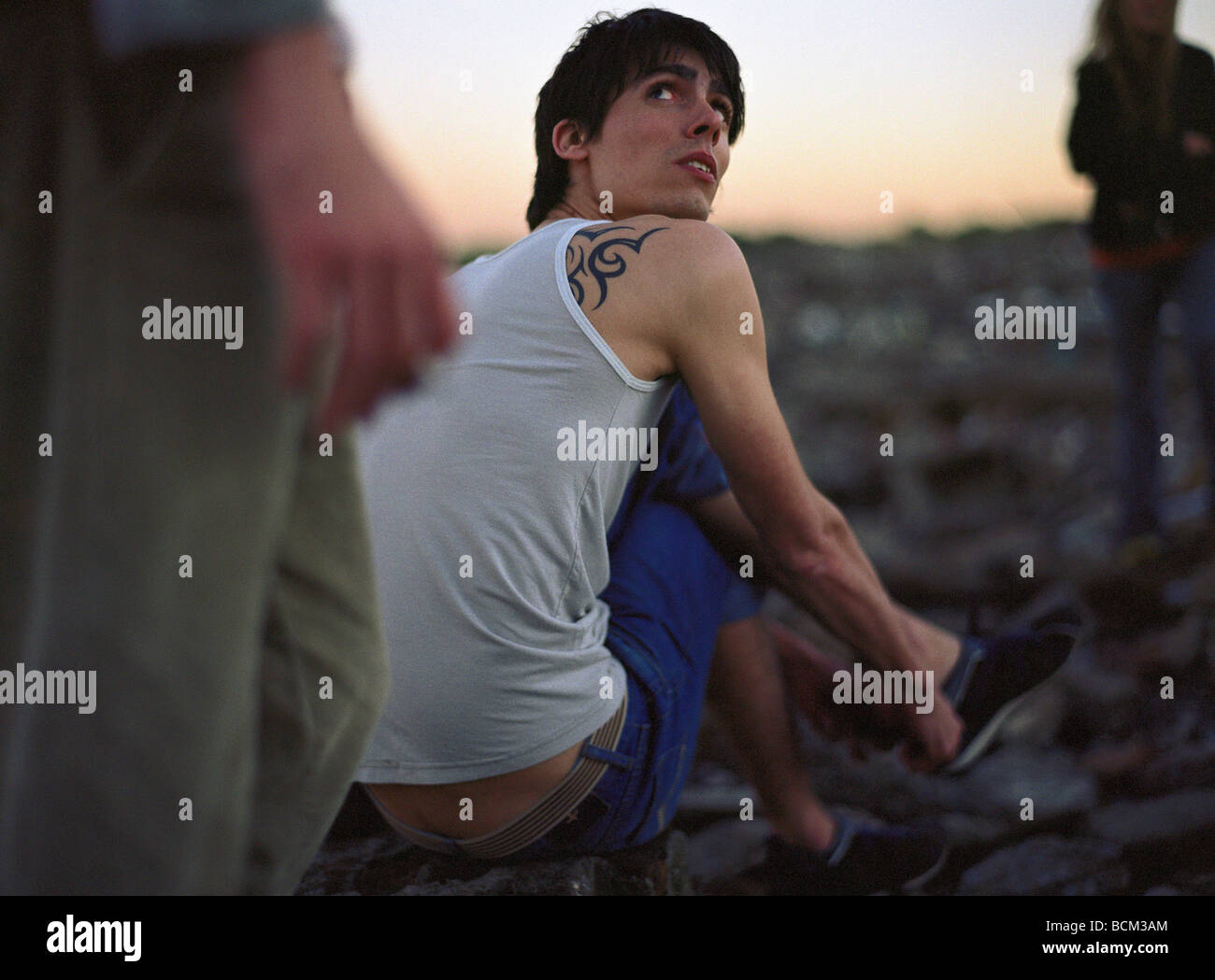 Young man sitting, looking up over shoulder at friend Stock Photo - Alamy