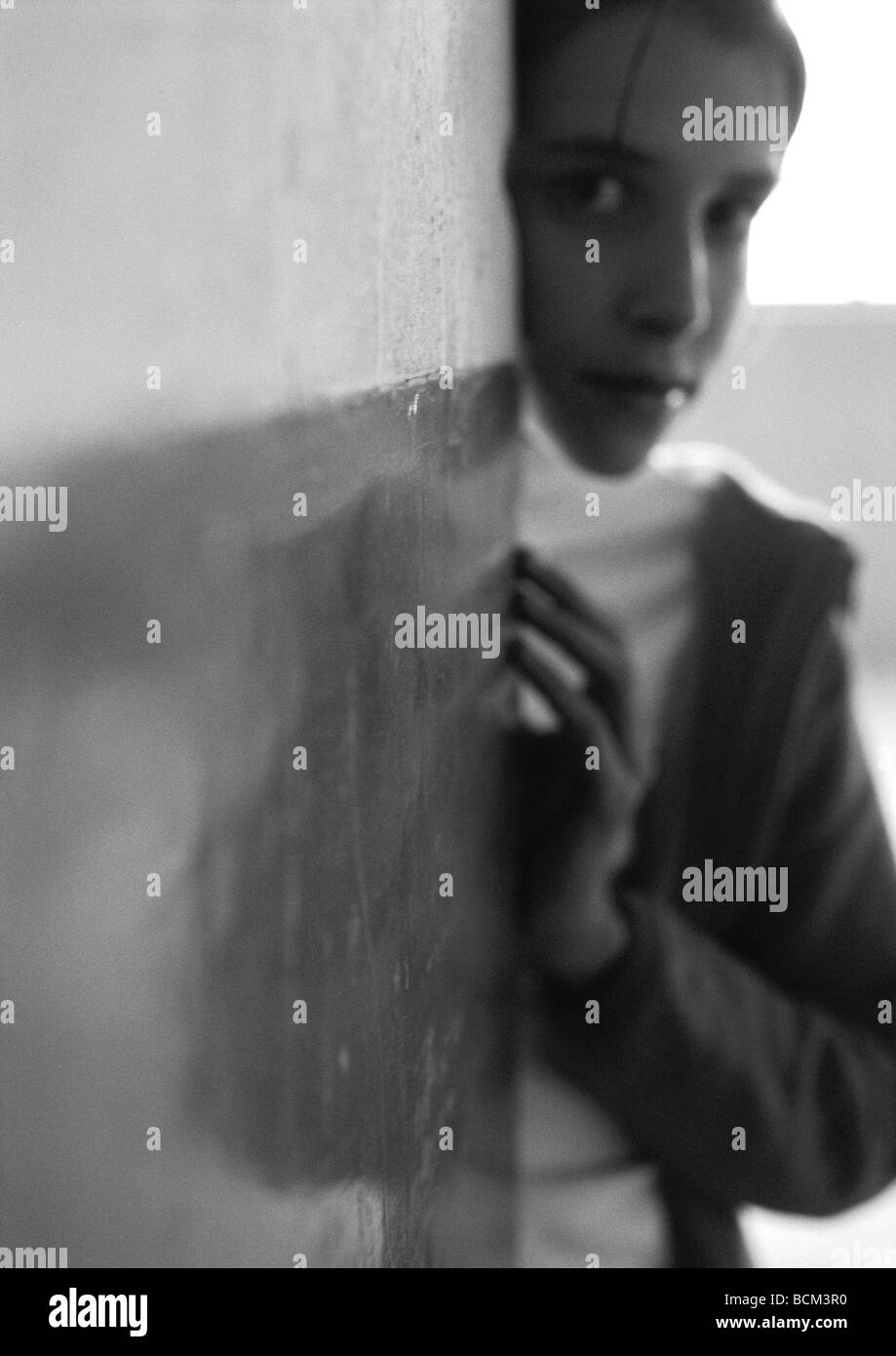 Girl peeking around corner, looking at camera Stock Photo - Alamy