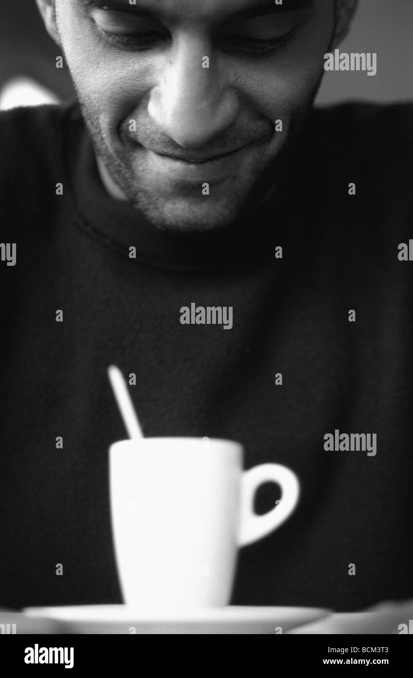 Man looking down at cup of espresso, smiling Stock Photo - Alamy