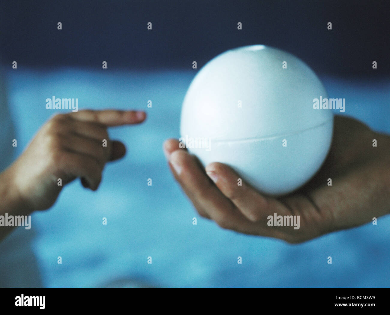 Adult hand holding out ball, child reaching to touch it with finger ...