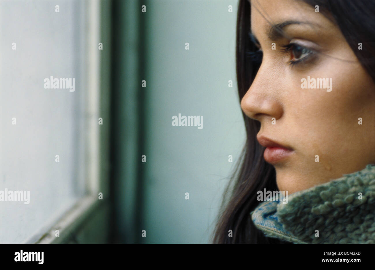 Young woman looking out window, crying, profile Stock Photo - Alamy