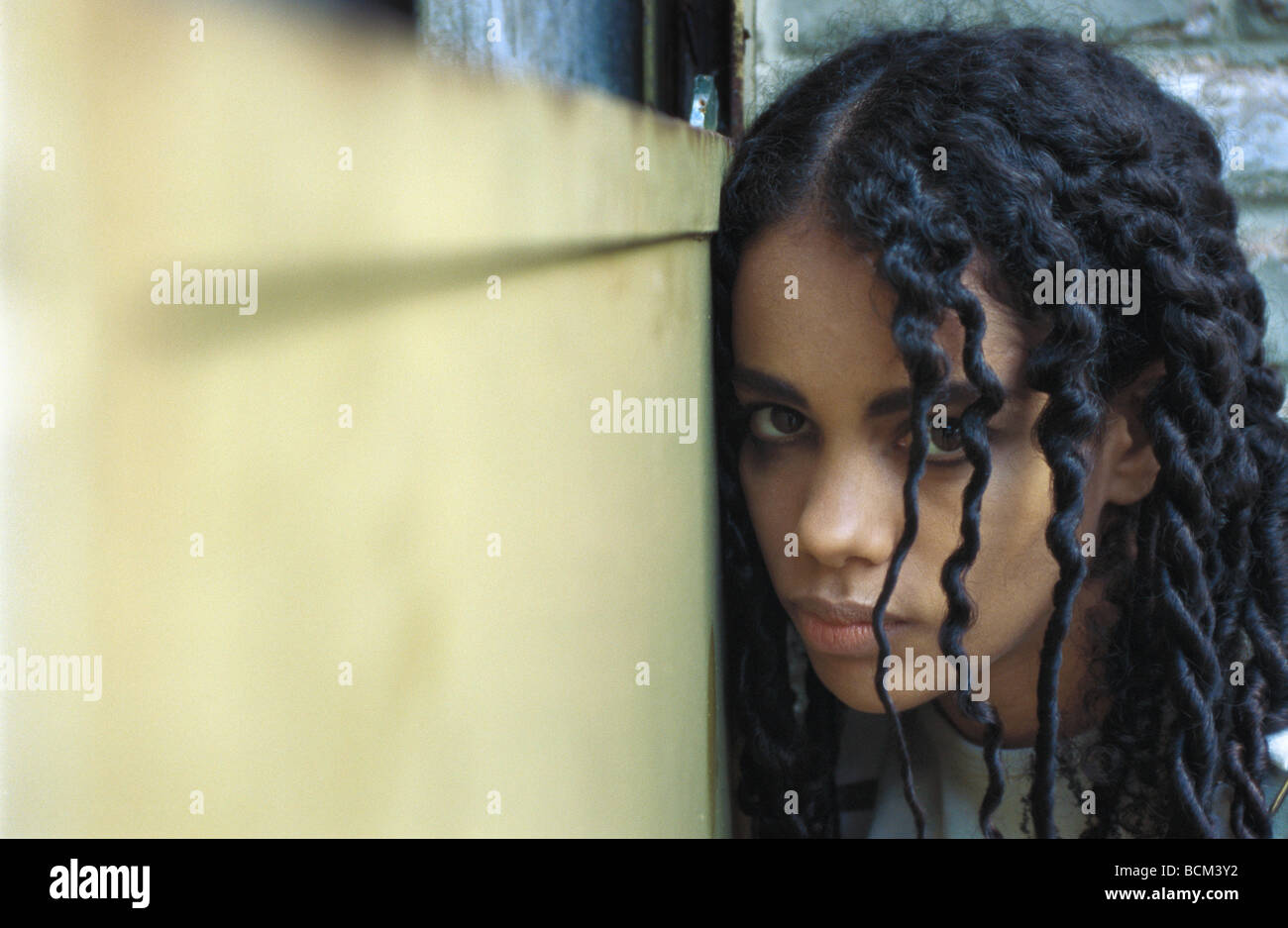 Young woman huddled in the corner, looking at camera Stock Photo - Alamy