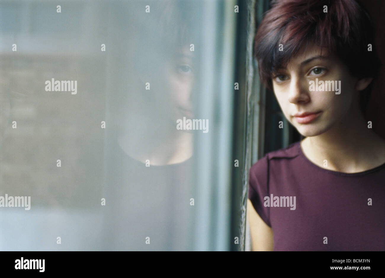 Young woman looking out of window Stock Photo - Alamy