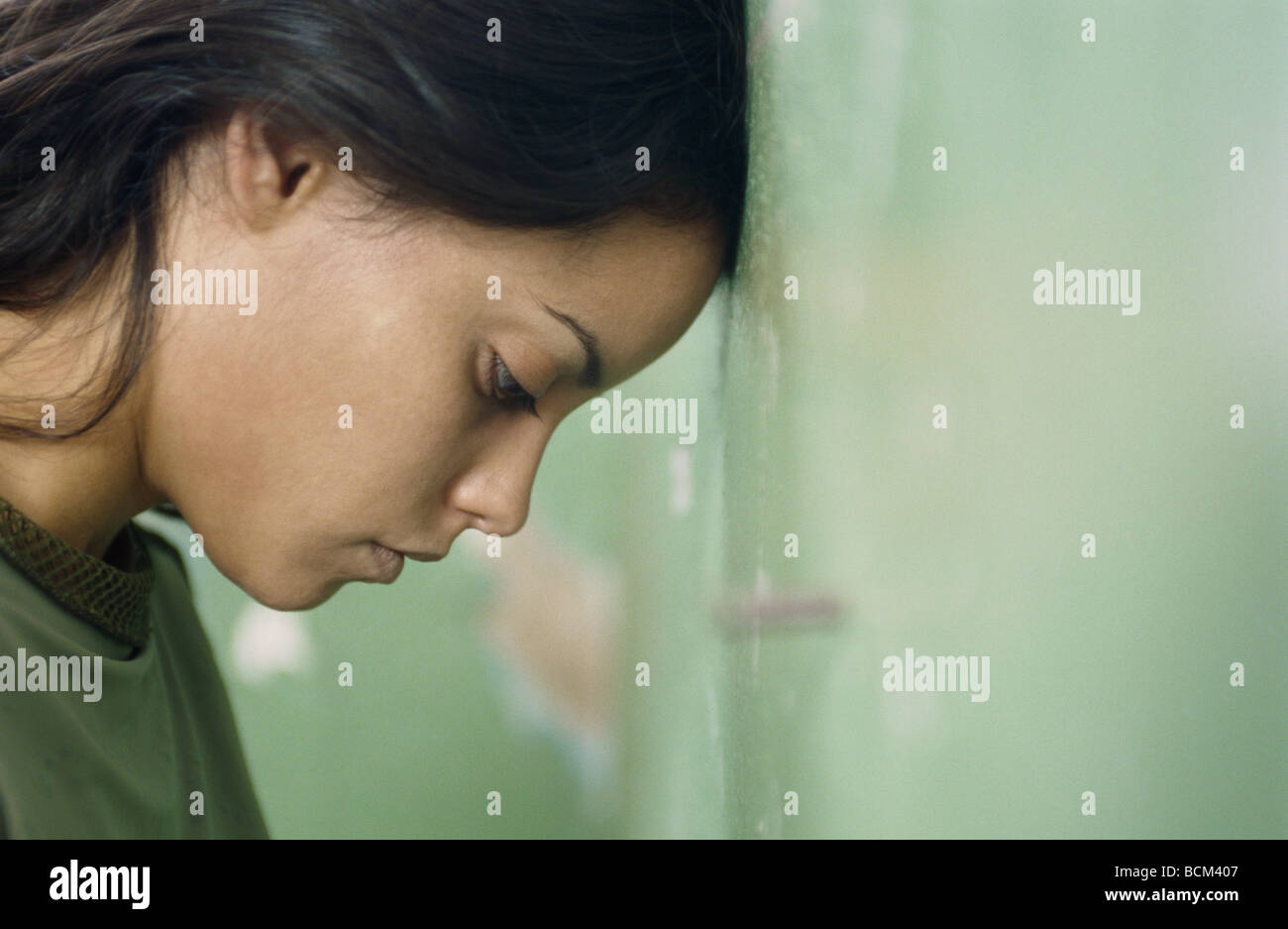 Young woman pressing her head against a wall, profile Stock Photo - Alamy