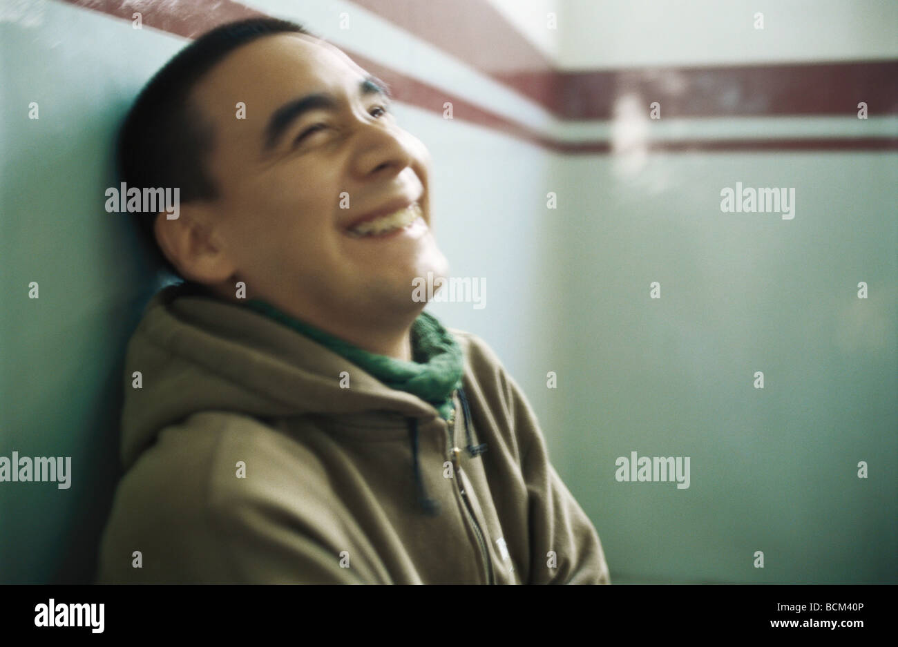 Young man leaning against wall with head back, laughing Stock Photo - Alamy