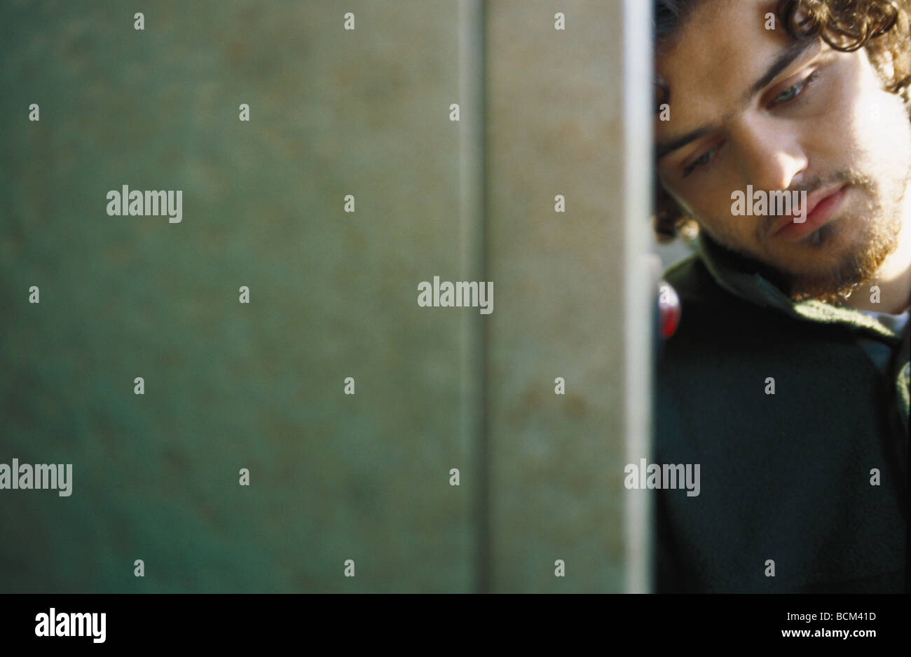 Young man leaning head against wall, looking down Stock Photo - Alamy