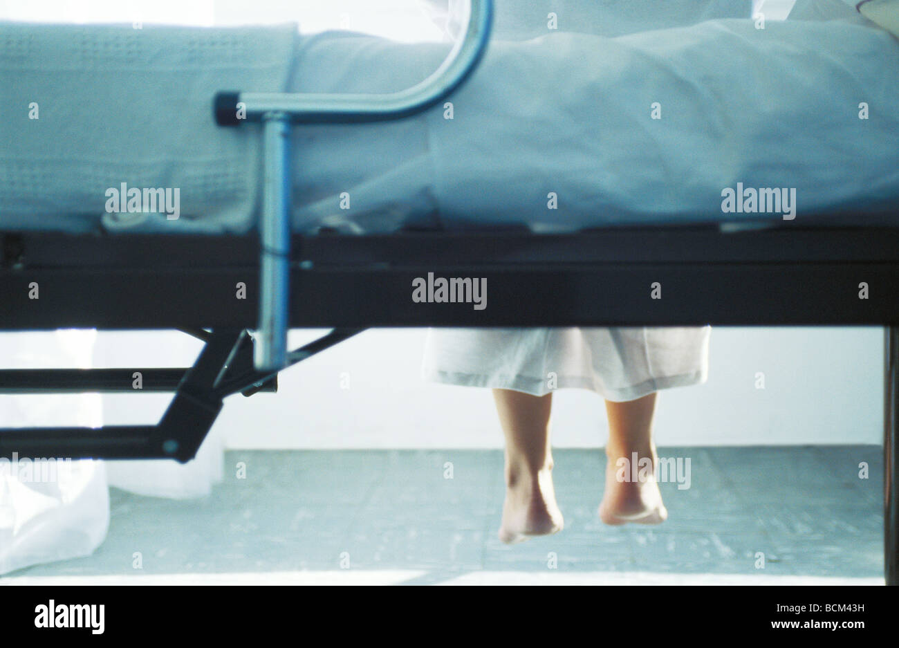 Person sitting on hospital bed with legs dangling, cropped Stock Photo ...
