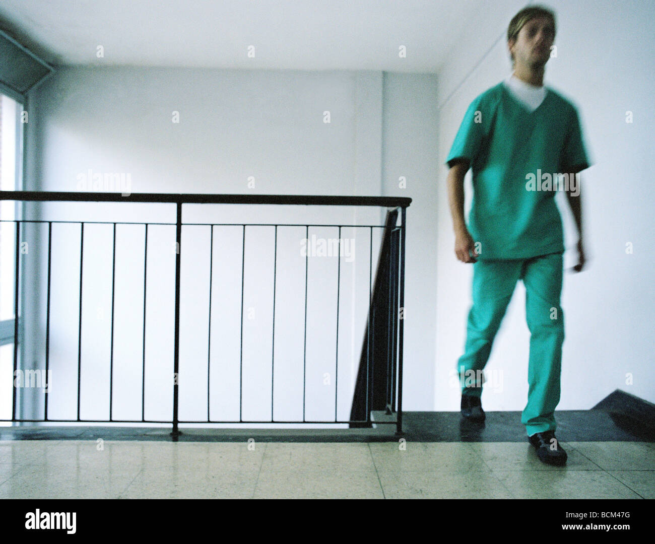 Young man in scrubs walking up stairs Stock Photo - Alamy