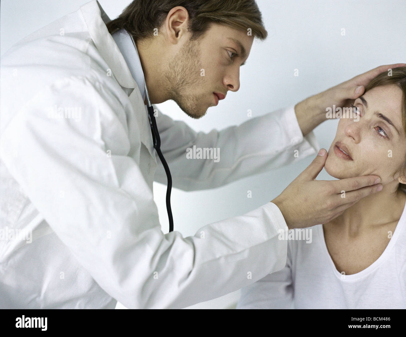 Doctor tilting female patient's head back to examine her eye, cropped ...