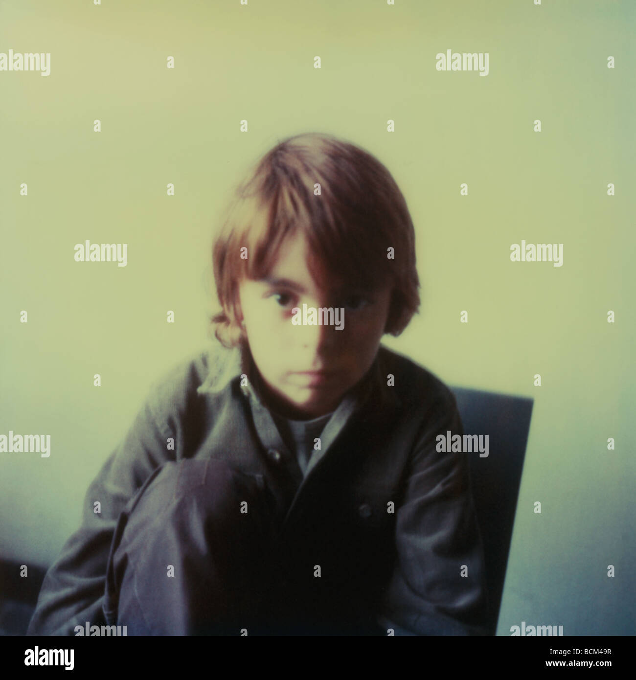 Boy sitting in chair, leaning forward and looking at camera, portrait ...