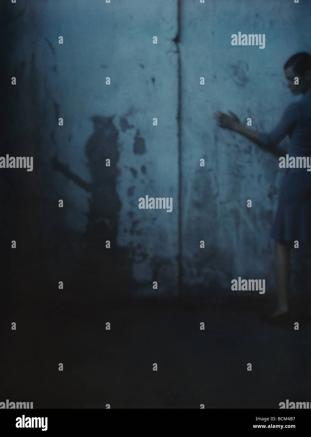 Young woman standing with hand against wall Stock Photo - Alamy