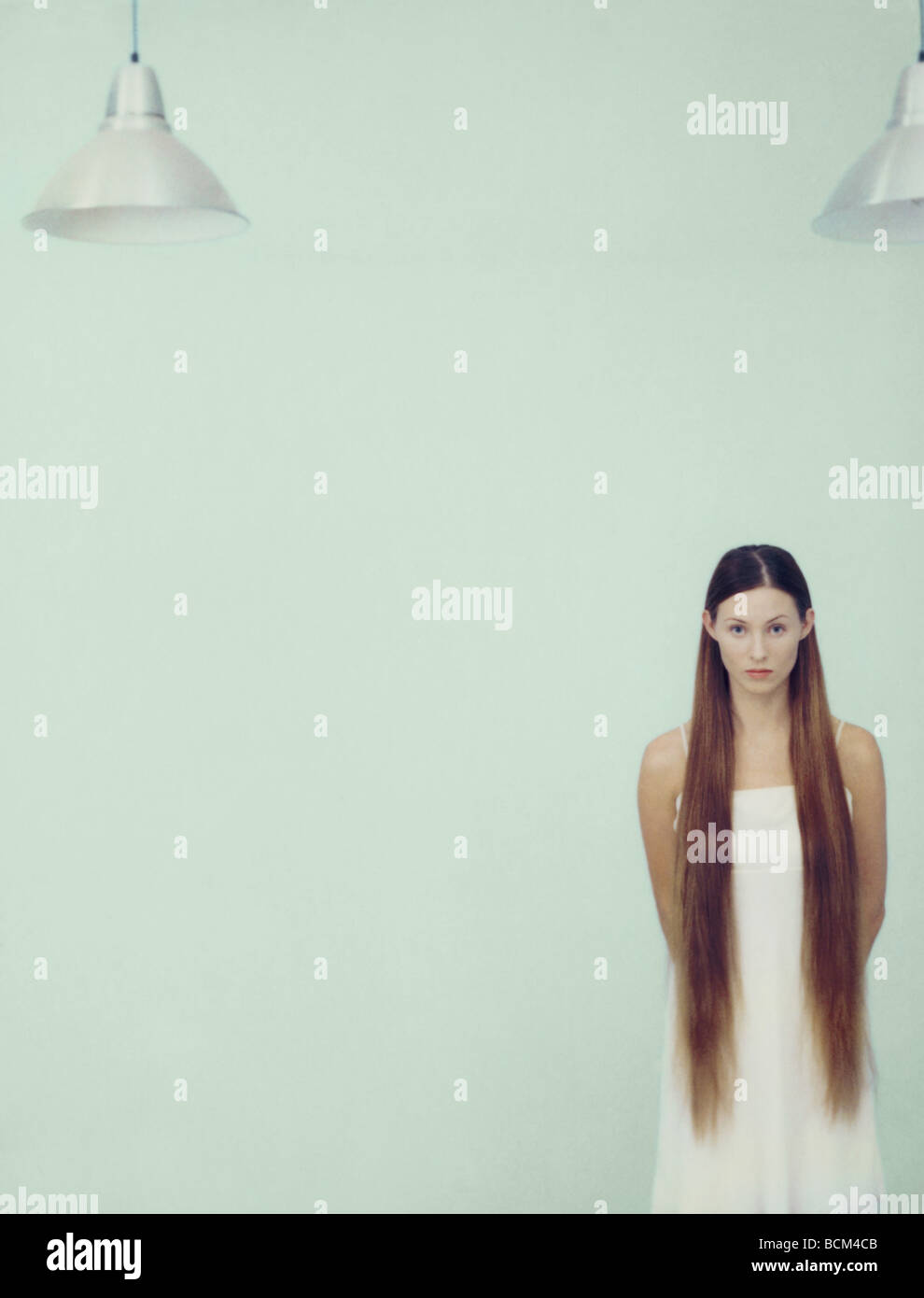 Young woman with long hair standing, looking at camera Stock Photo - Alamy