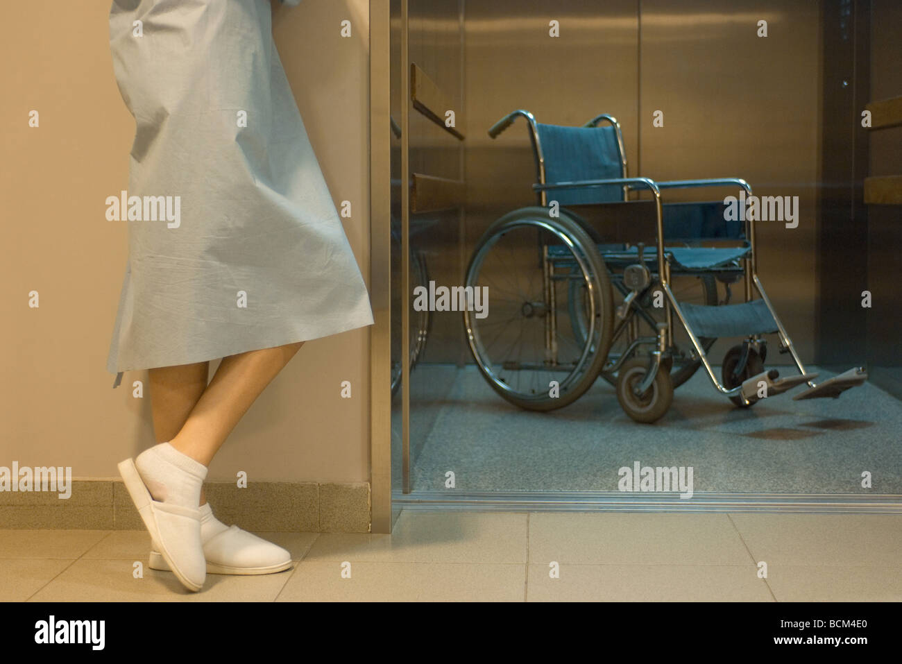 Hospital patient waiting beside open elevator, wheelchair inside ...