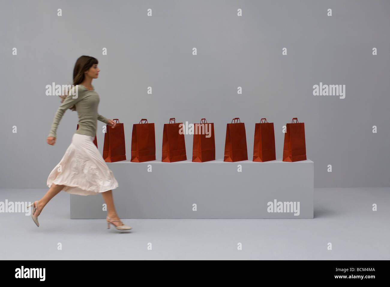 Woman walking past row of shopping bags, side view Stock Photo - Alamy