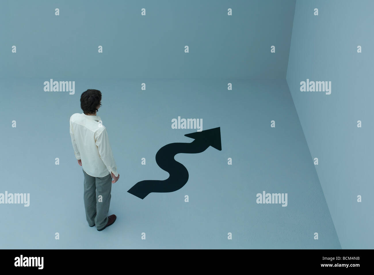 Man standing before curvy arrow pointing toward corner, high angle view ...