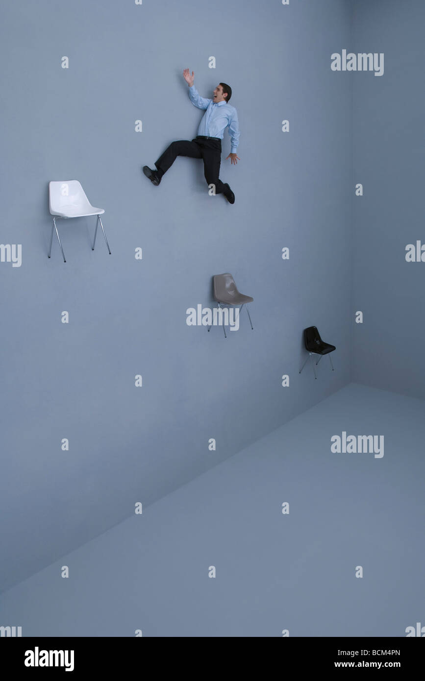 Chairs arranged as steps in mid-air, man leaping from one to the next ...