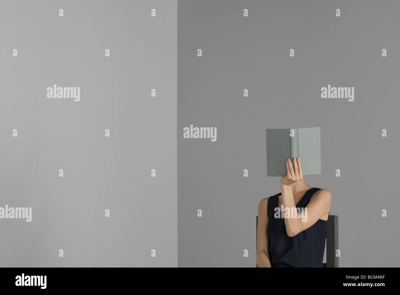 Woman holding open book in front of face Stock Photo - Alamy