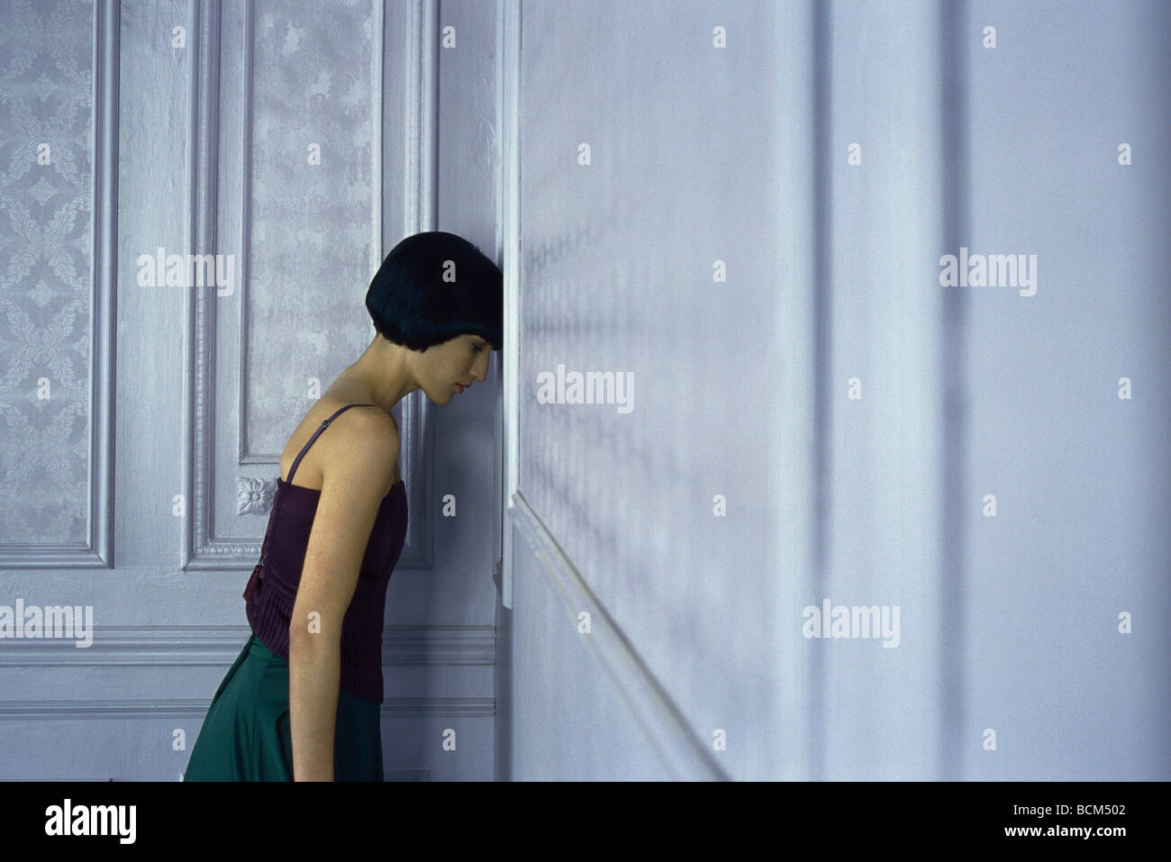 Woman standing in corner, leaning head against wall, eyes closed Stock ...