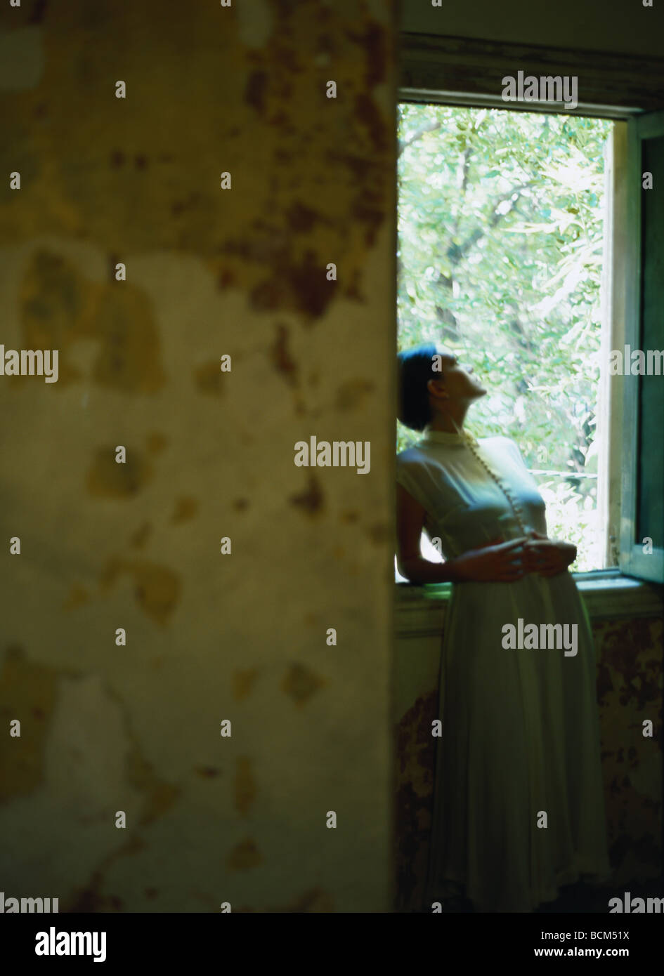 Woman leaning out window with hands on stomach, looking up Stock Photo ...