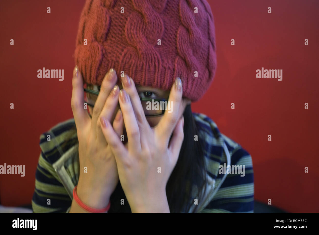 Female covering face with hands, peeking at camera Stock Photo - Alamy