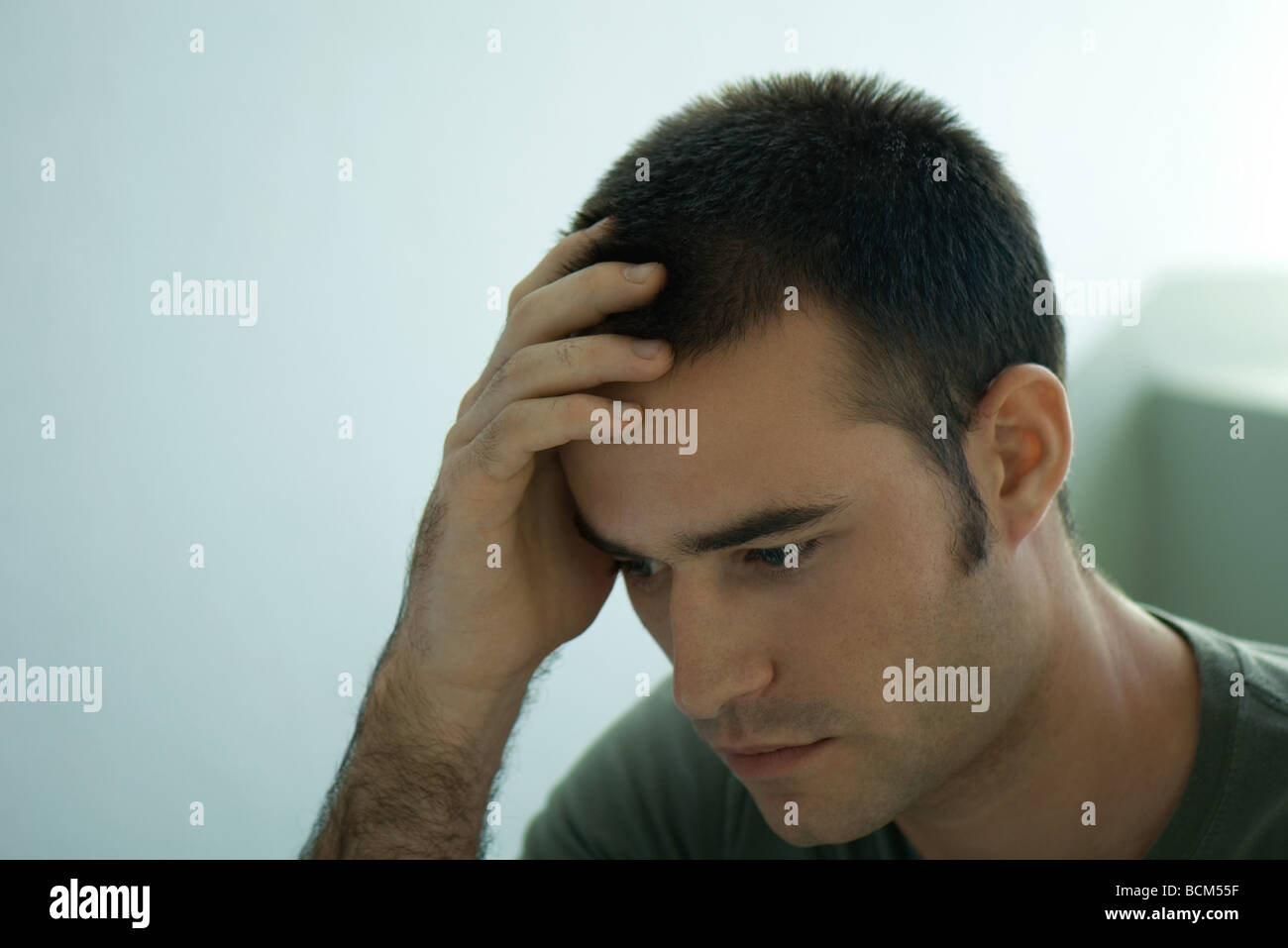 Man holding head, looking down Stock Photo - Alamy