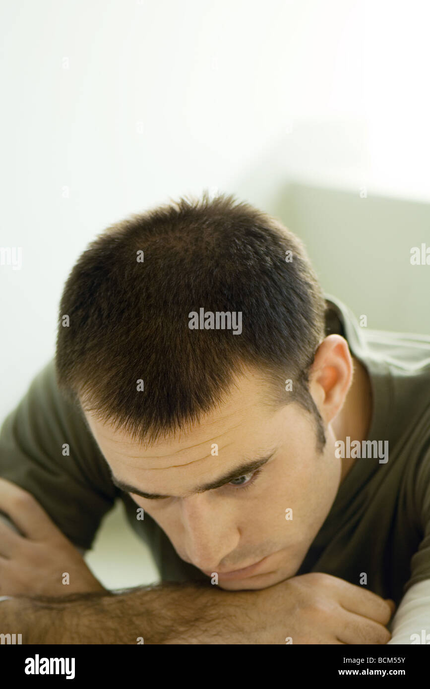 Man resting head on arm, looking down Stock Photo - Alamy