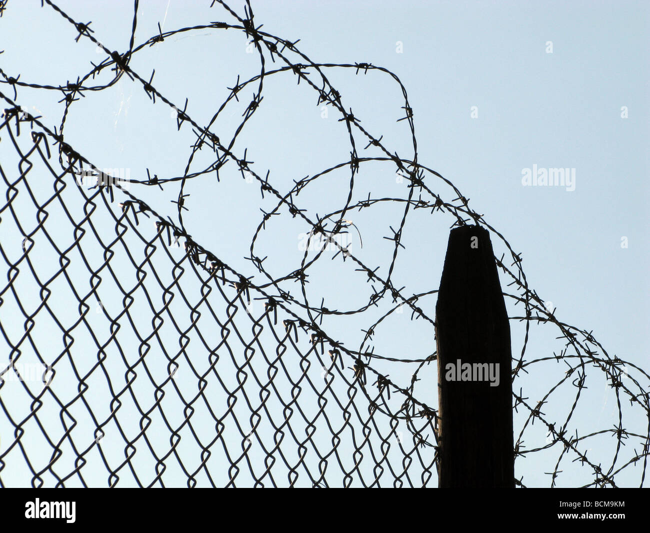 dark high wall fence with barbed wire outdoors Stock Photo - Alamy